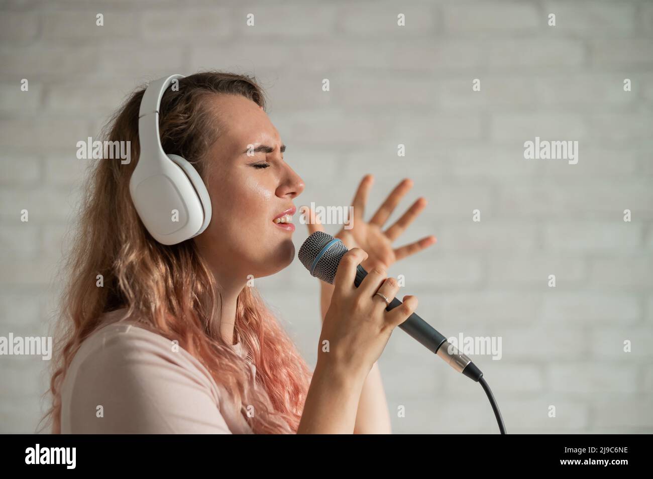 Close-up portrait of a caucasian woman with curly hair singing into a ...