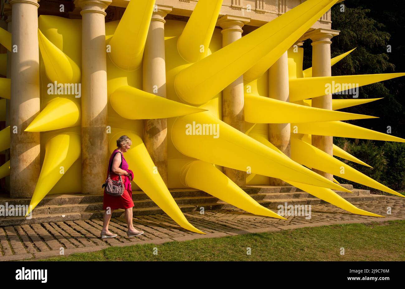 A woman dressed in red and purple walks past a giant yellow inflatable ...