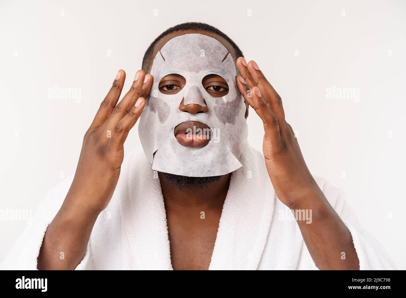 A young man with paper mask on face looking shocked with an open mouth ...