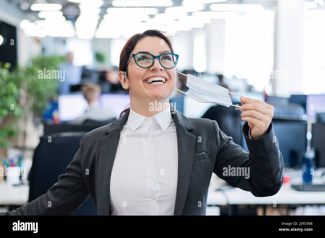 Business woman takes off the mask in the office at the end of ...