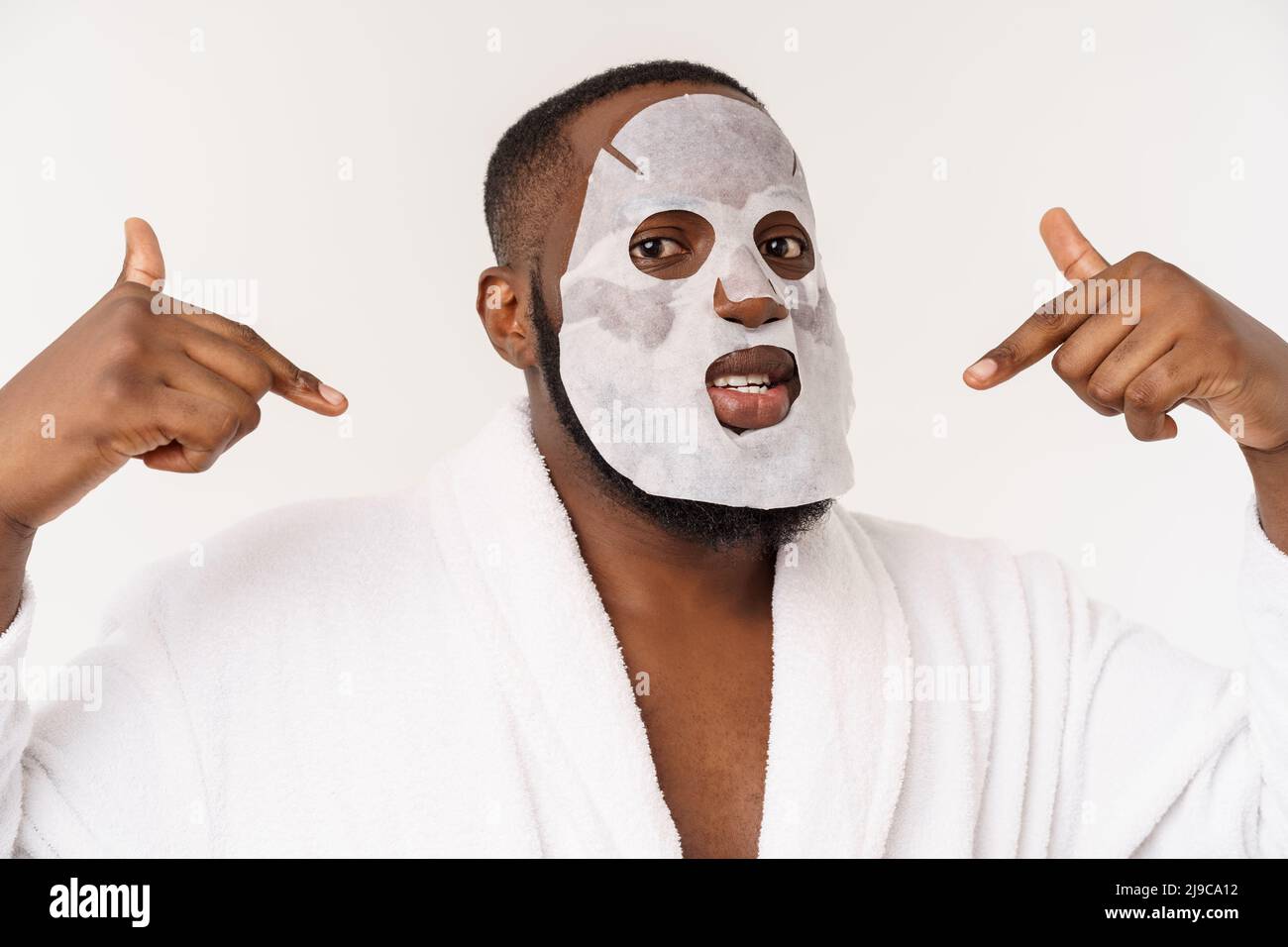 A young man with paper mask on face looking shocked with an open mouth ...