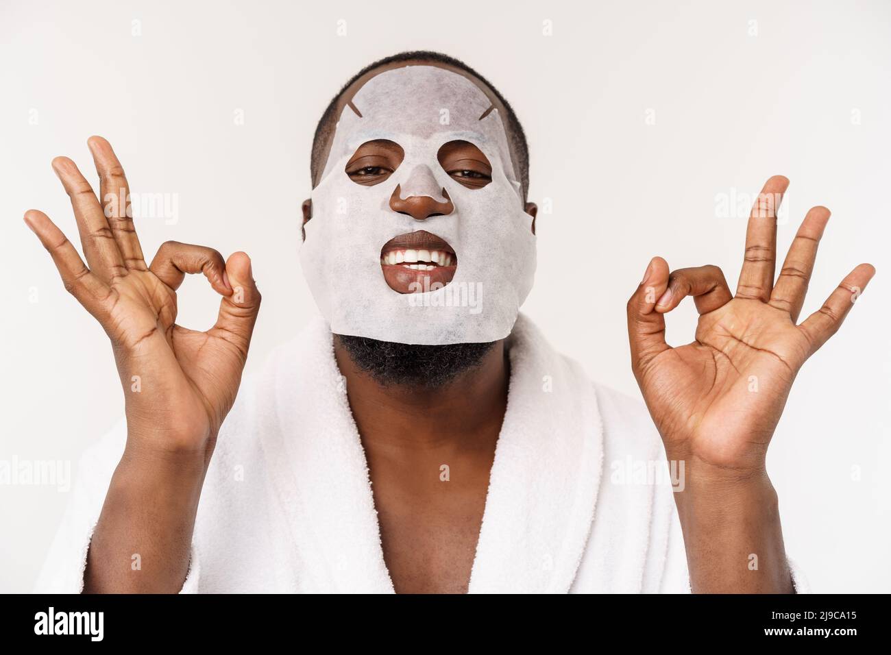 A young man with paper mask on face looking shocked with an open mouth ...