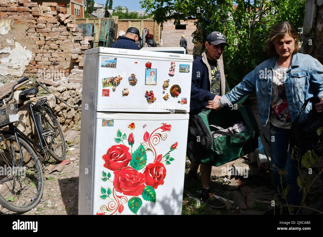 Neighbors help a lady transport her refrigerator from the private house ...
