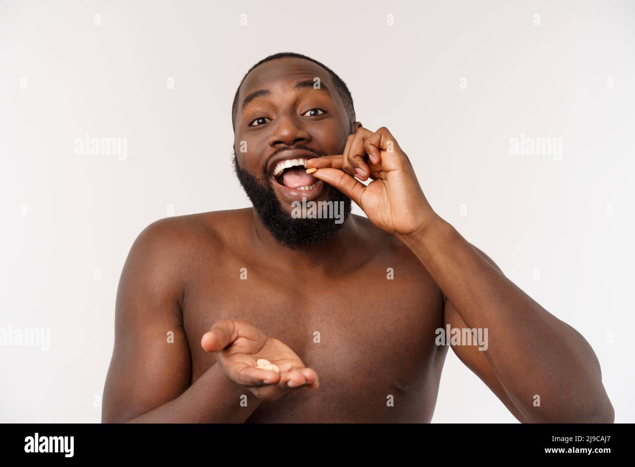 Sick African American guy eating medicine pill. Black man standing on ...