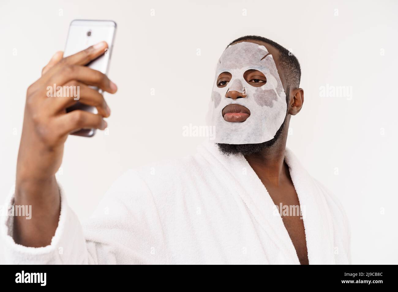 A young man with paper mask on face looking shocked with an open mouth ...