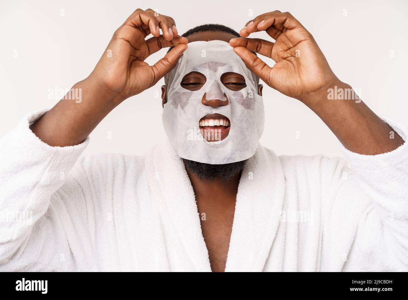 A young man with paper mask on face looking shocked with an open mouth ...