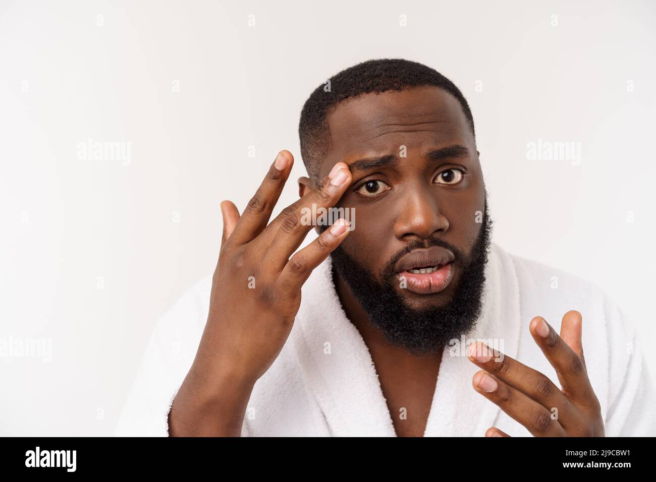 African American man looks at pimples on face. Acne. Male hygiene ...