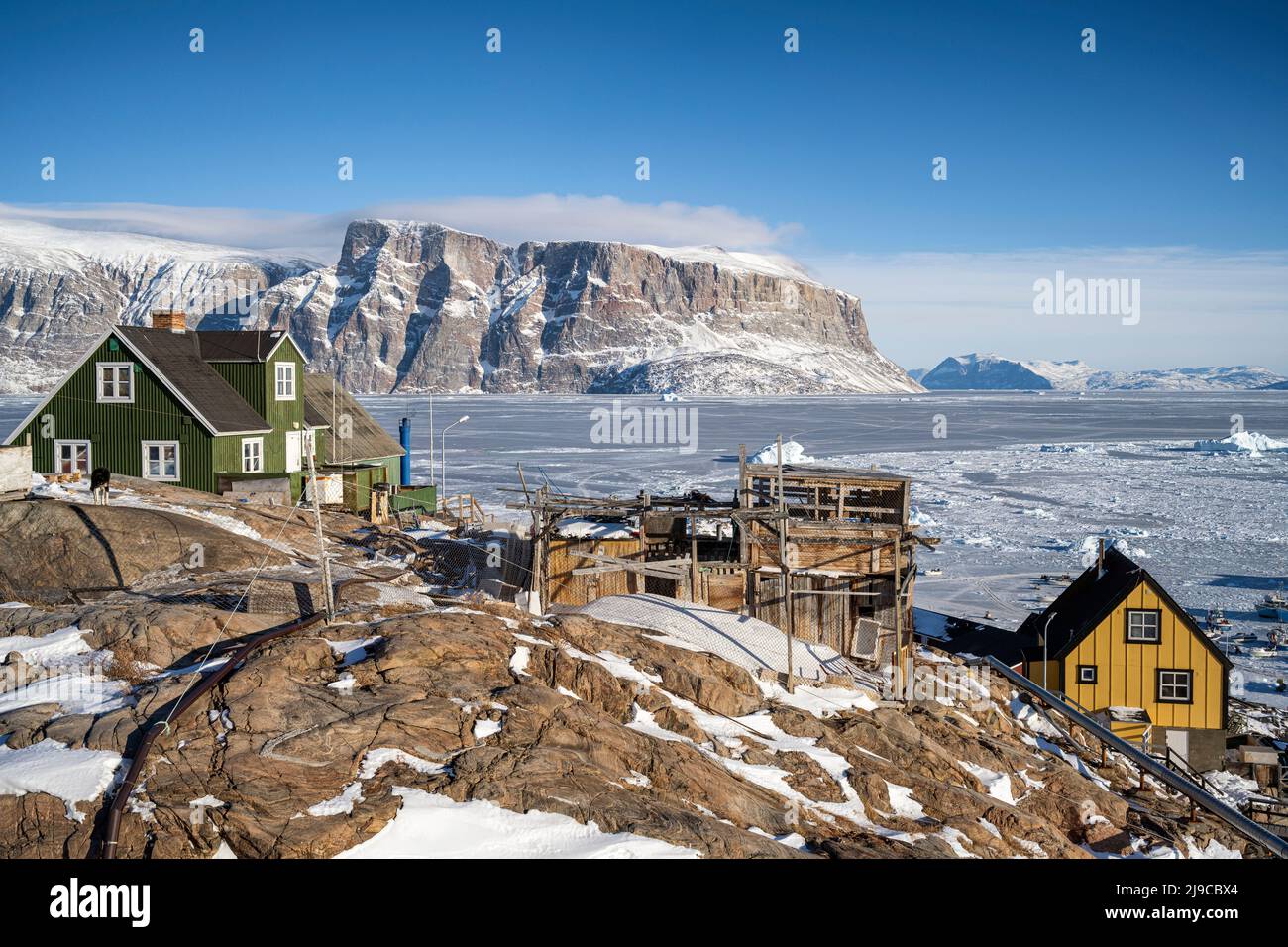 Ramshackle buildings cling to the edge of the rocks at Uummannaq in ...