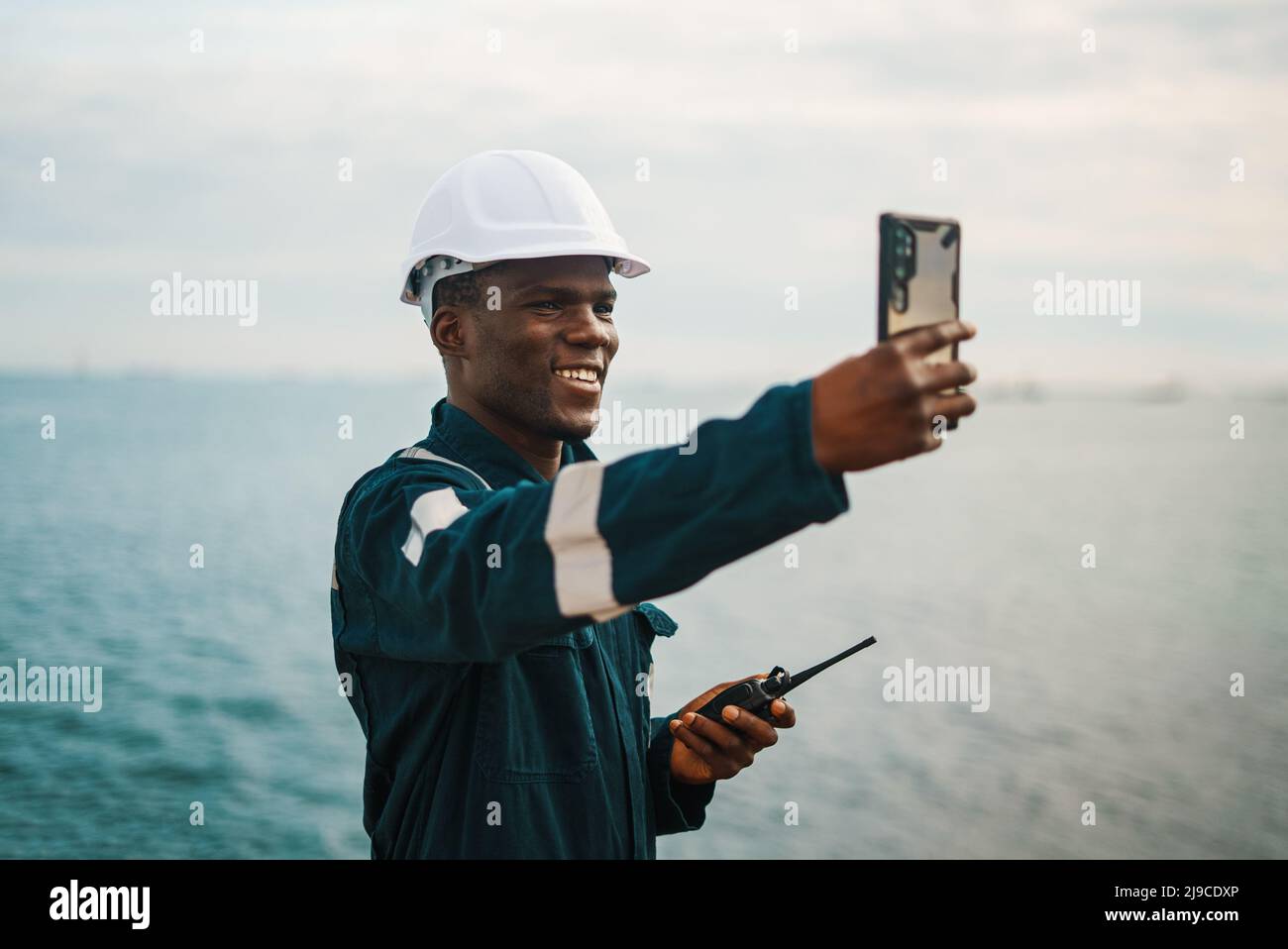Black maritime worker making video call in sea Stock Photo - Alamy