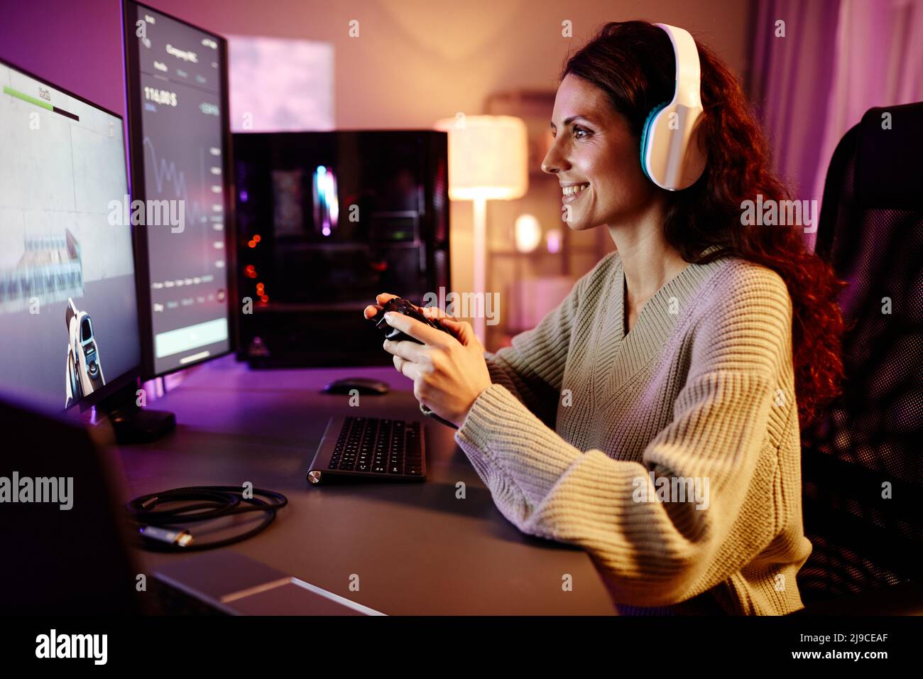 Modern young adult Caucasian woman wearing headphones playing shooter ...