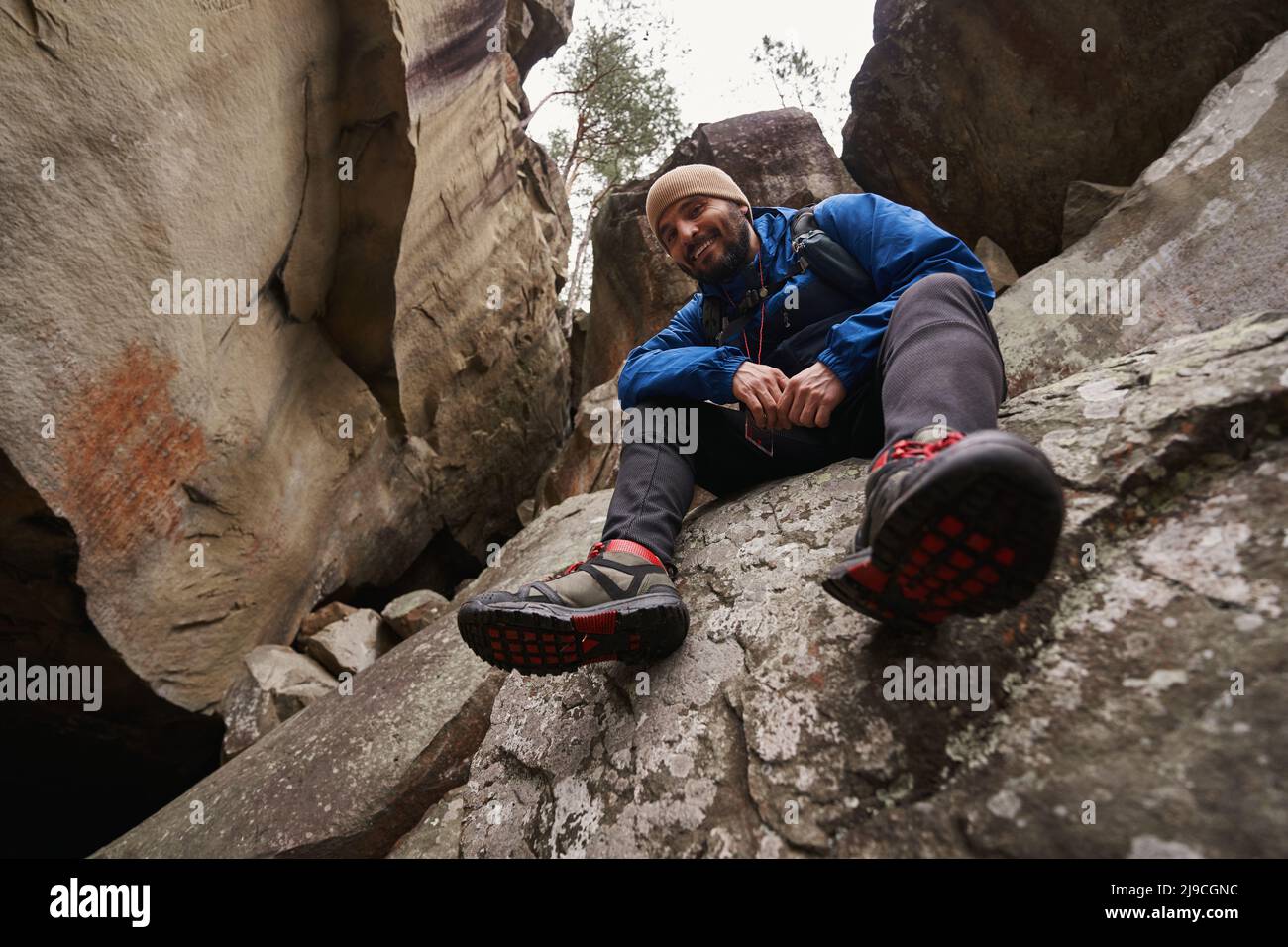 Happy male person sitting on the rock Stock Photo - Alamy
