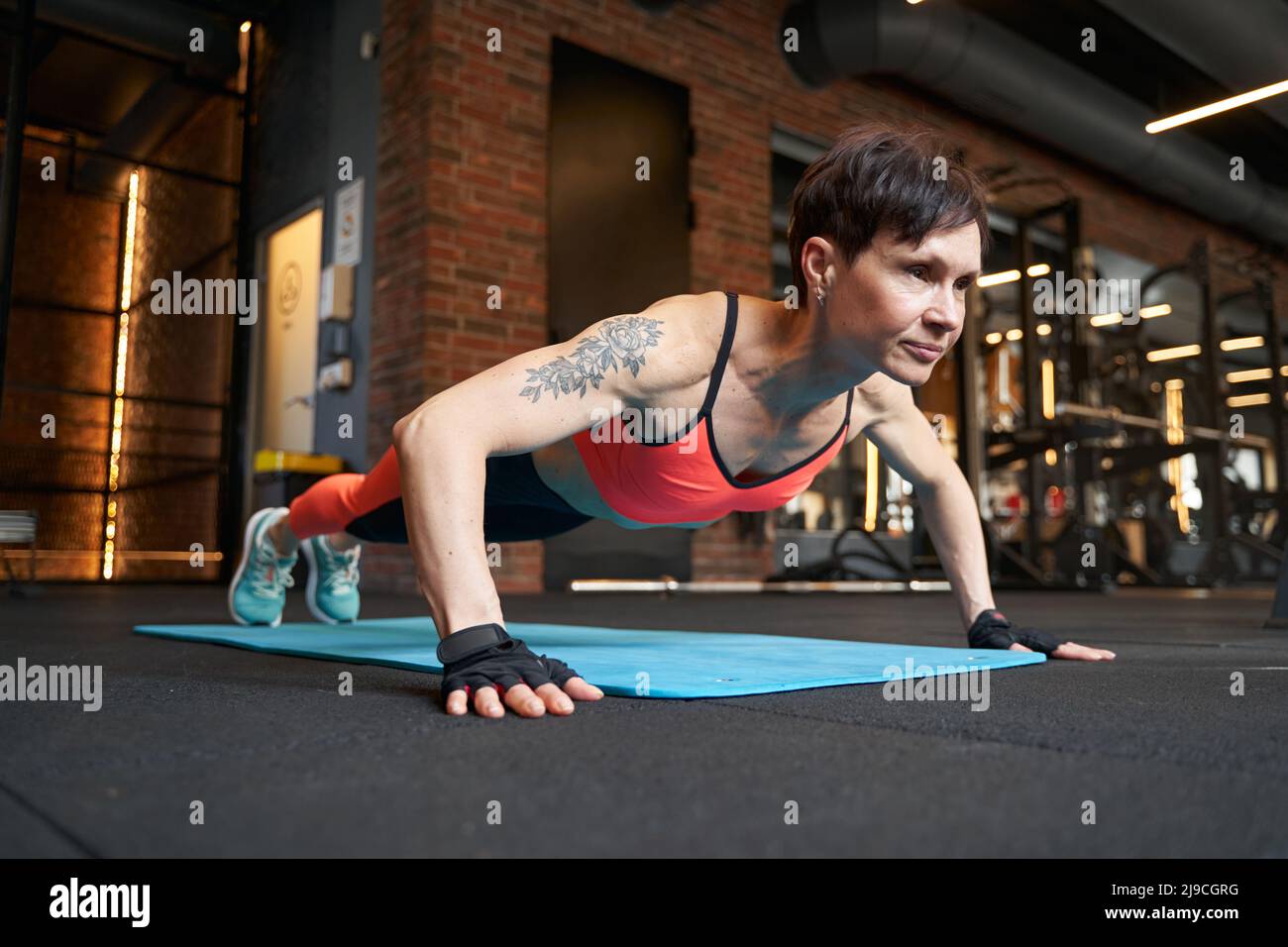 Muscular woman performing push-up on gym floor Stock Photo - Alamy