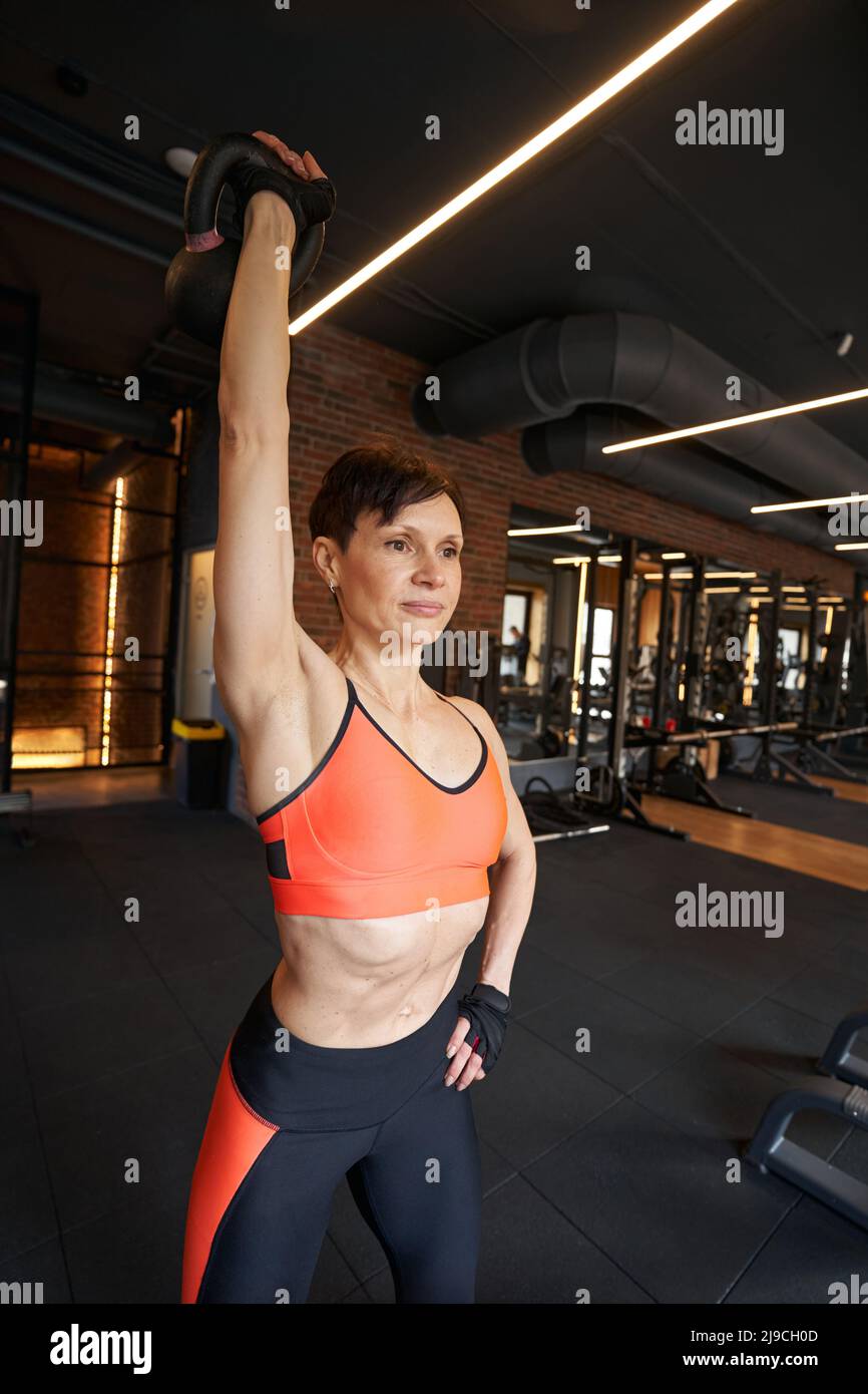 Athletic woman performing weight-lifting exercise at gym Stock Photo ...