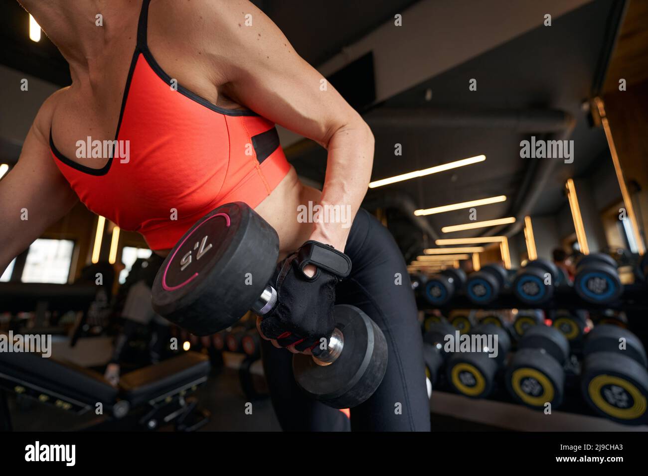 Female athlete performing dumbbell exercise at gym Stock Photo - Alamy