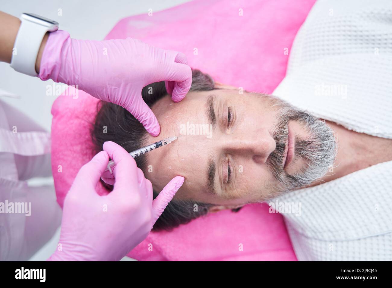 Adult bearded man undergoing cosmetic injection forehead area in ...