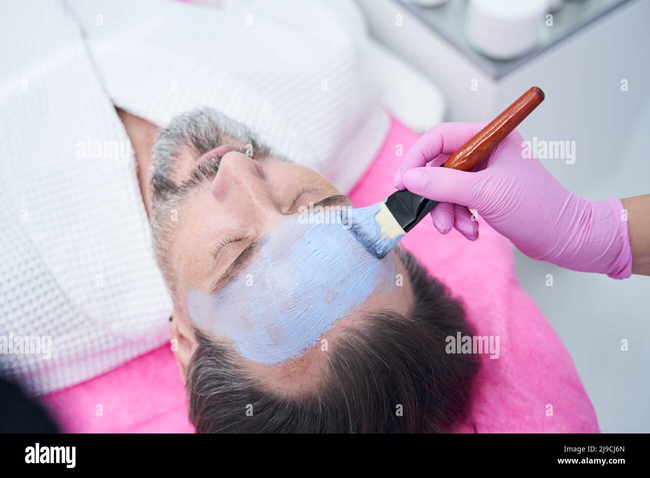 Cosmetologist applying mask to client face at beauty salon Stock Photo ...