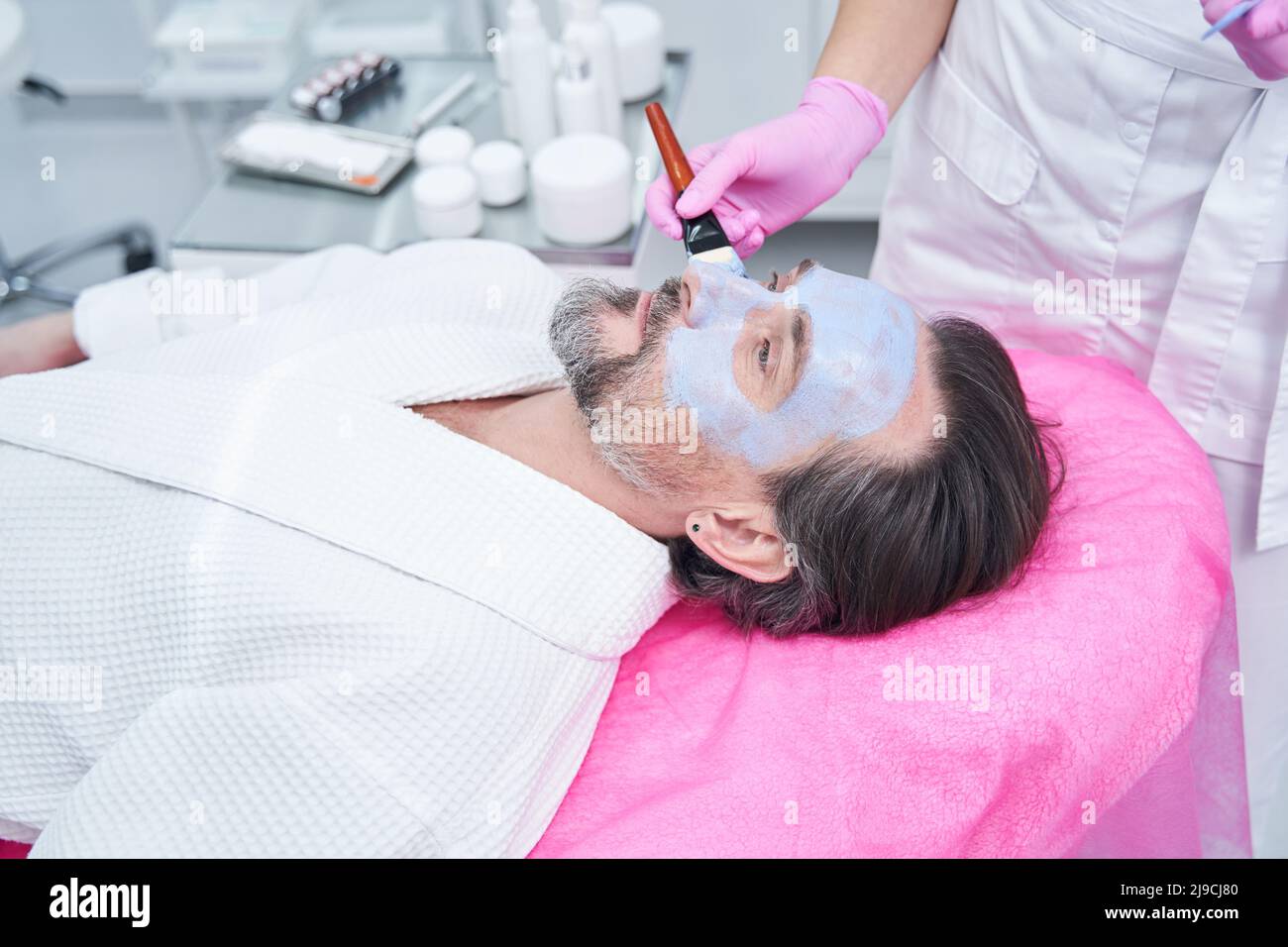 Doctor in cosmetology office applying mask to male face Stock Photo - Alamy