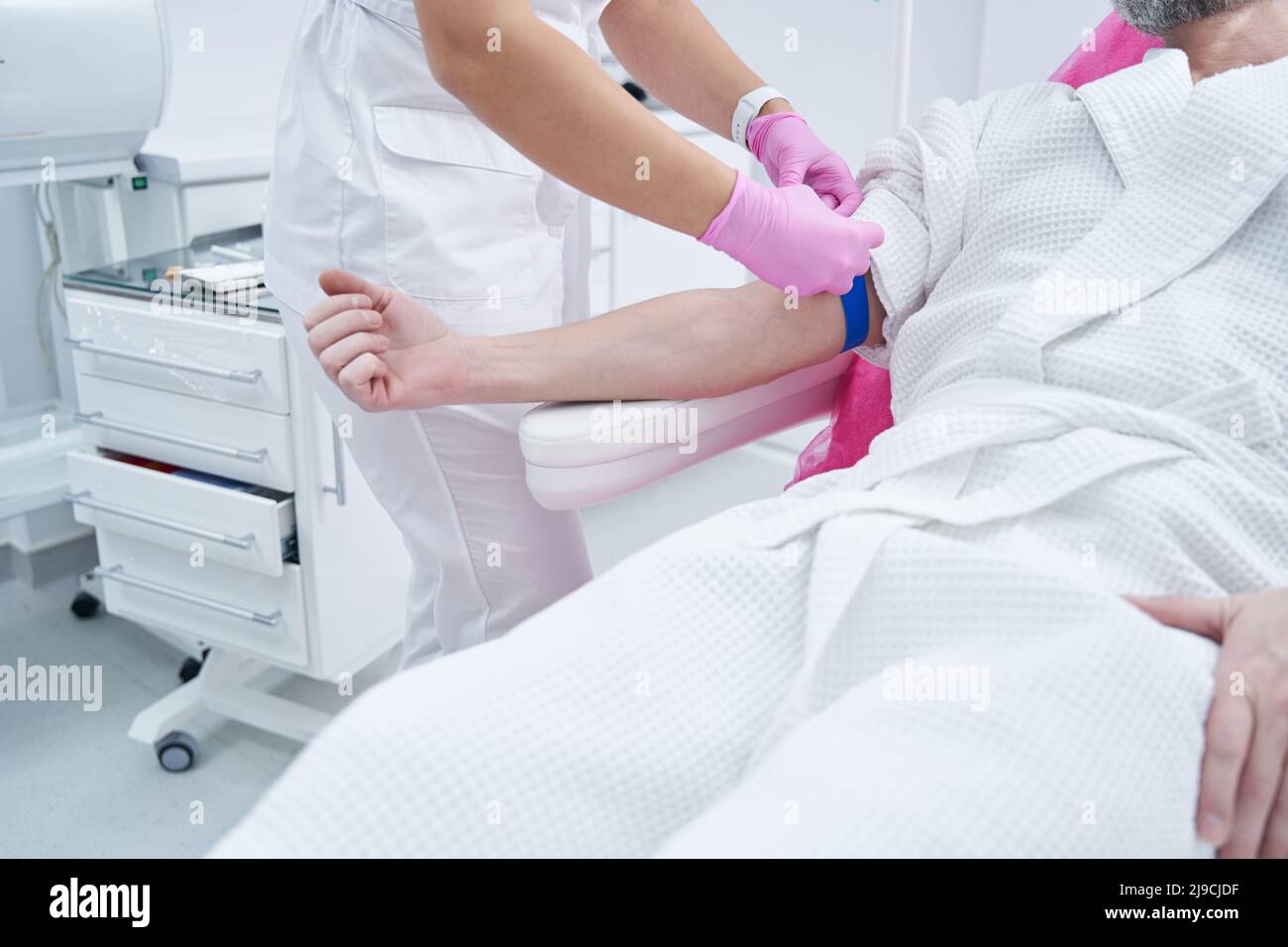 Doctor cosmetologist preparing male client arm for insertion of drip ...