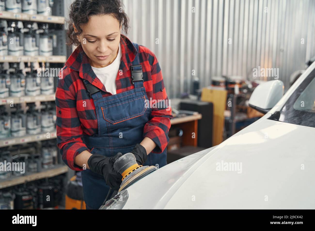 Attentive female master grinding body of auto Stock Photo - Alamy