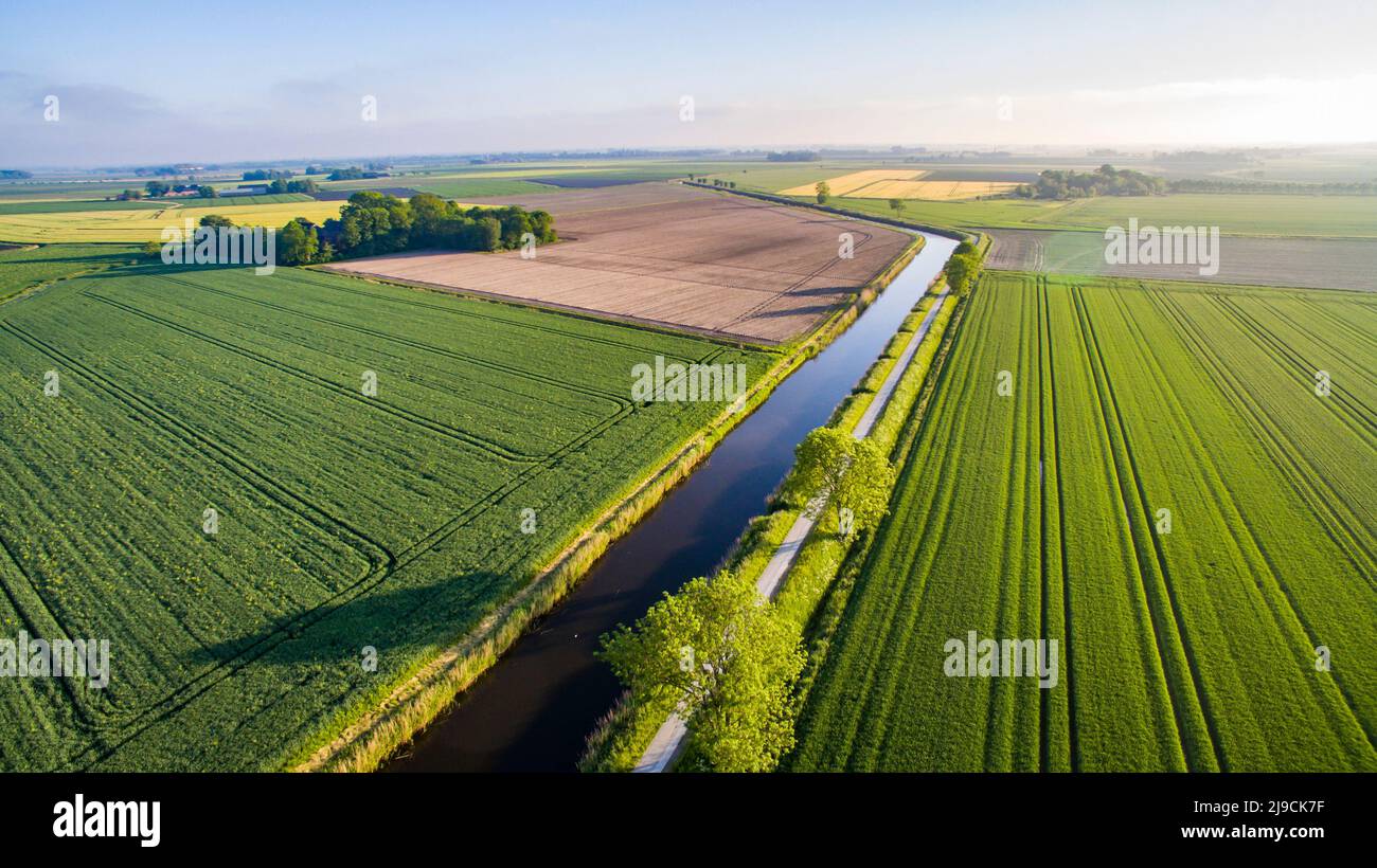 Straight road next to water canal in flat country Stock Photo - Alamy