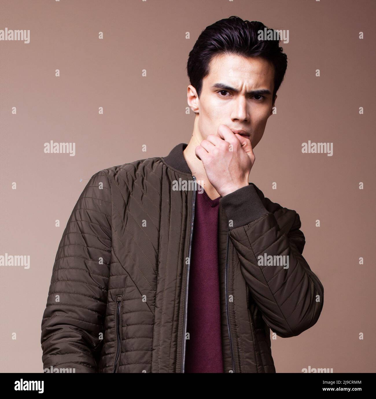 young pretty asian man posing in fashion style on light brown ...