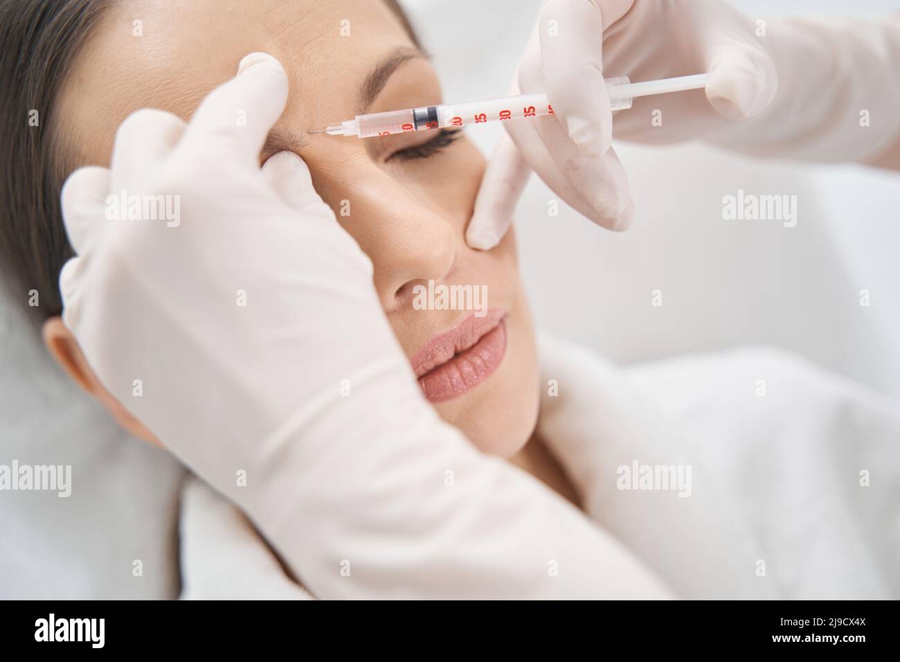 Beautician doing face lifting injection in woman forehead Stock Photo ...