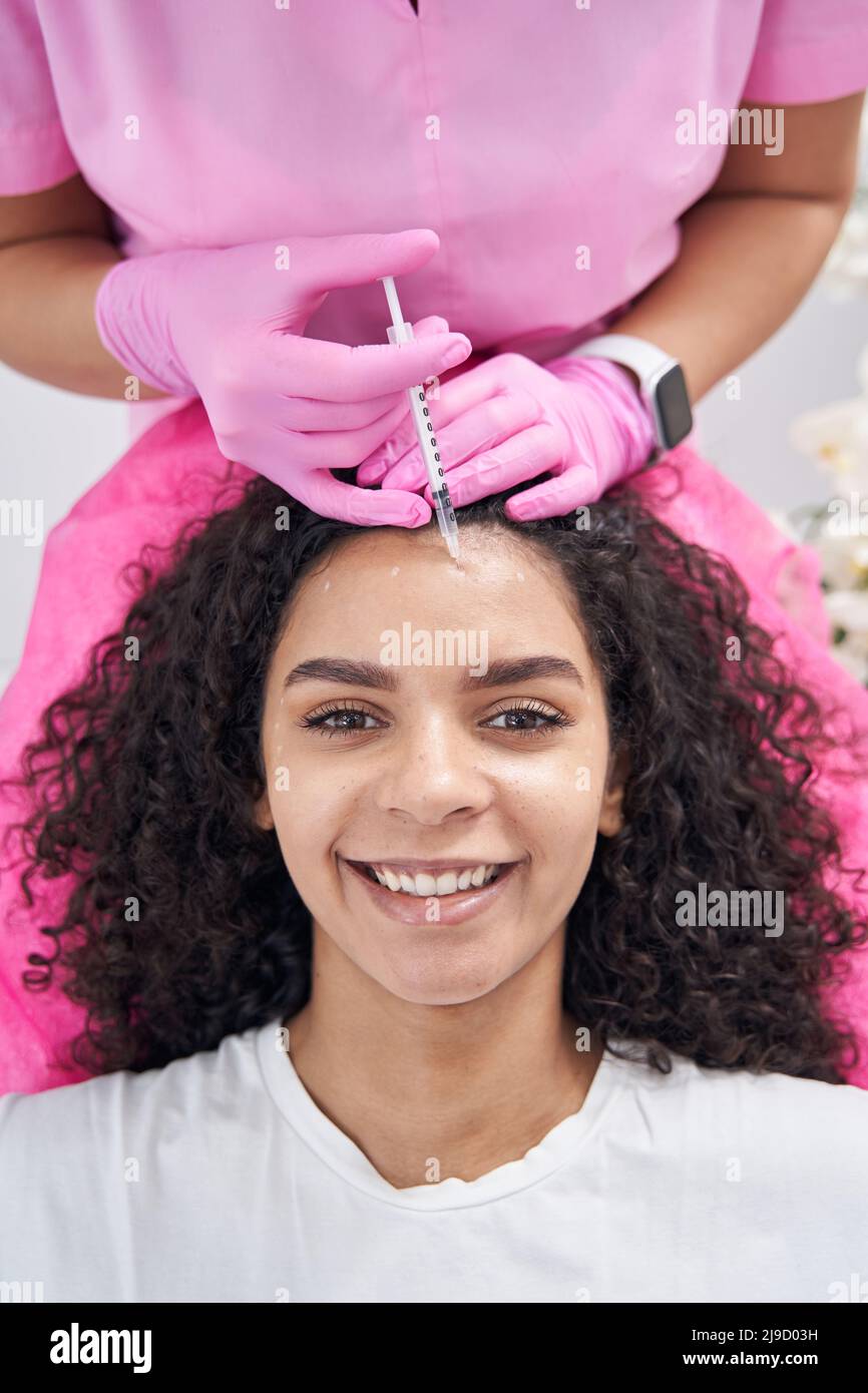 Beautician performing minimally invasive injections for facial ...