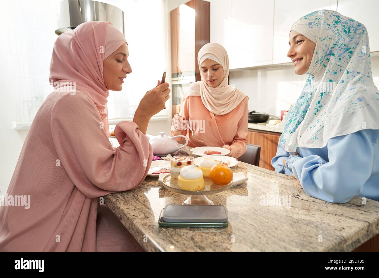 Muslim women having lunch together and chatting in kitchen Stock Photo ...