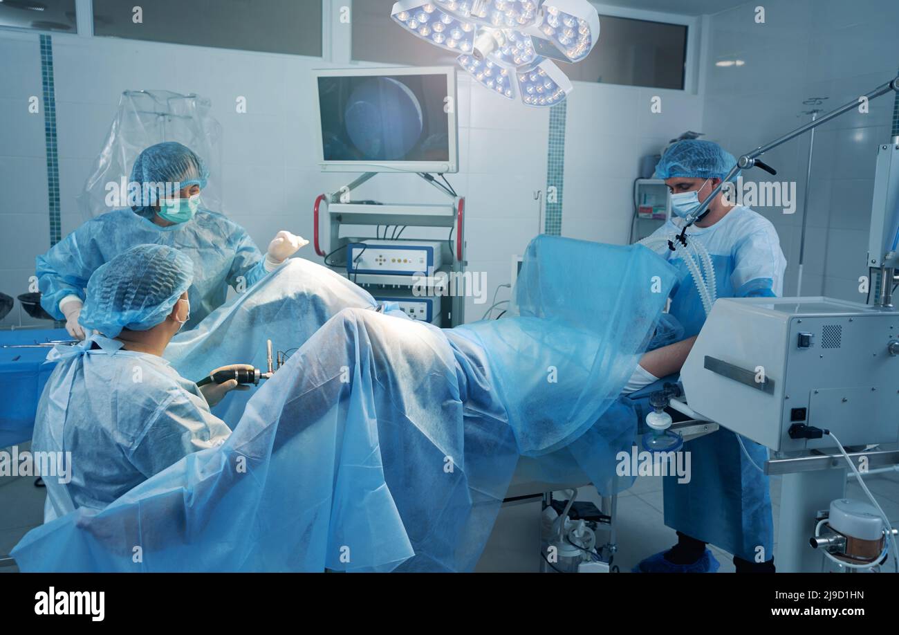 Team of surgeons viewing inside patient body with laparoscopic camera ...
