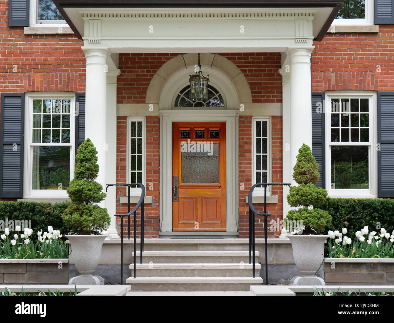 House with portico entrance and elegant wood grain front door Stock ...