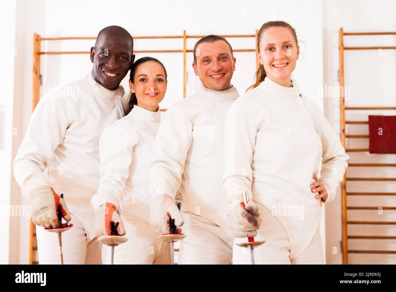 Group of positive fencers standing with foils together at fencing ...