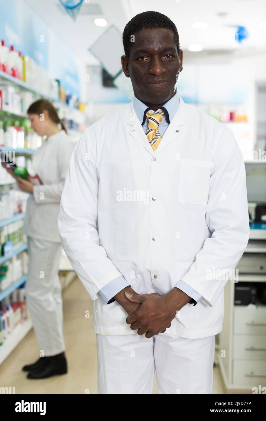 smiling male pharmacist standing in interior of pharmacy Stock Photo ...