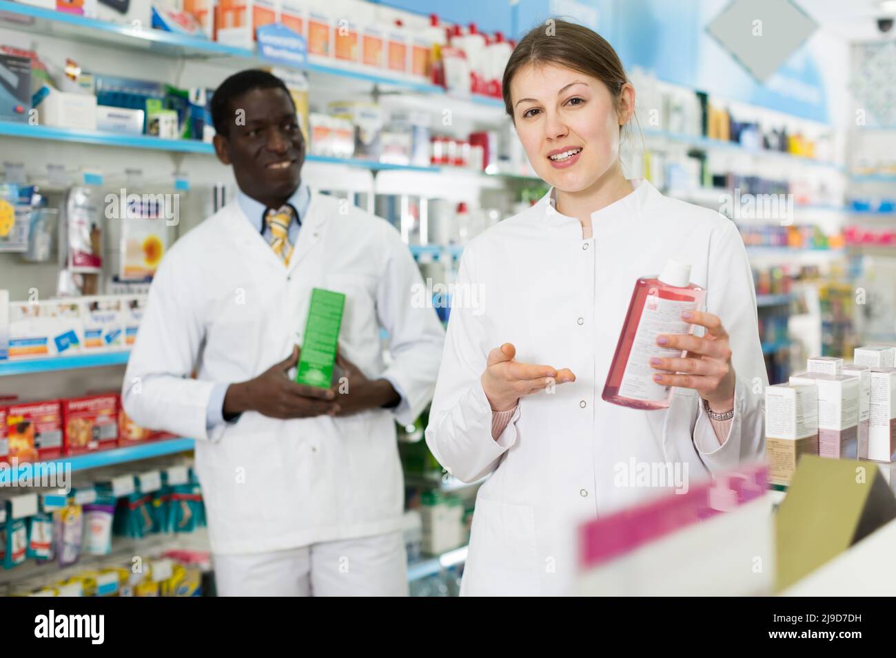 Portrait of two pharmacists offering medication in modern pharmacy ...