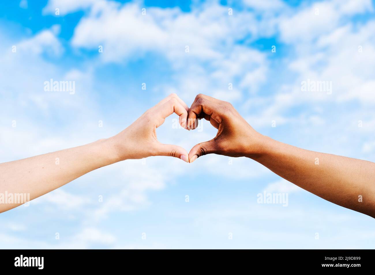 Two multiethnic hands join together to form a shape heart with a blue ...