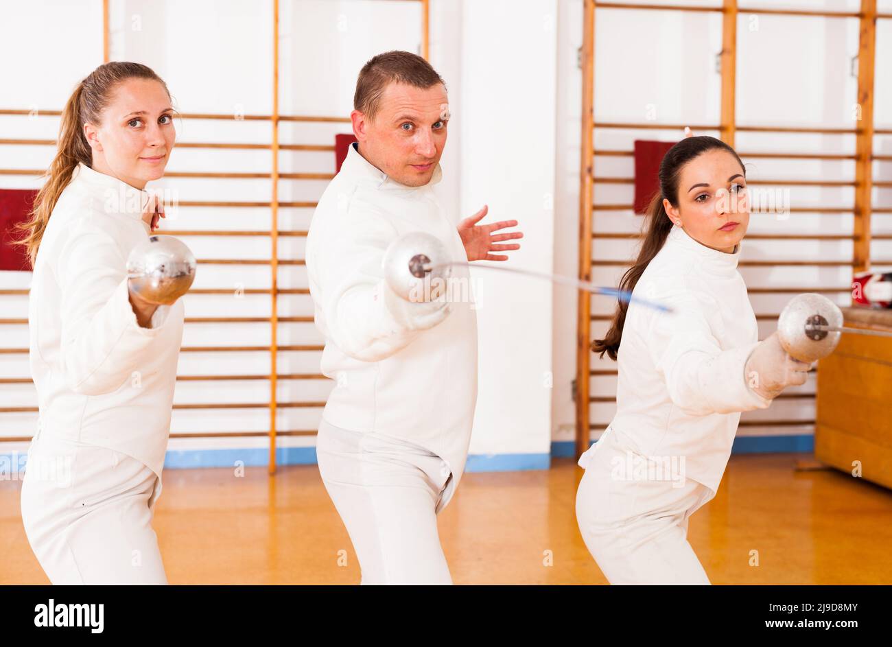 Man and women fencers practicing movements together at fencing workout ...