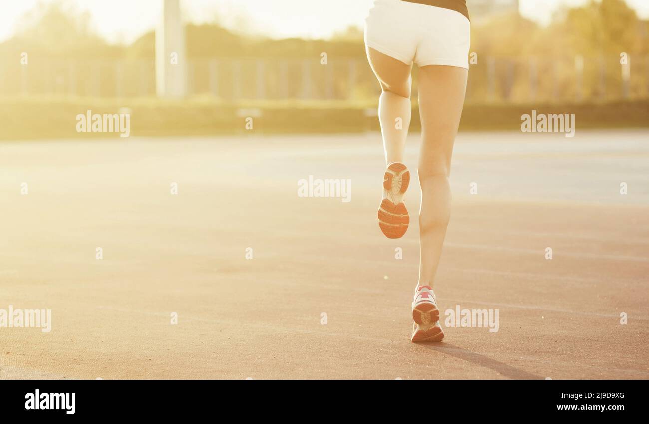 young woman runner in sneakers training on stadium outdoor Stock Photo ...