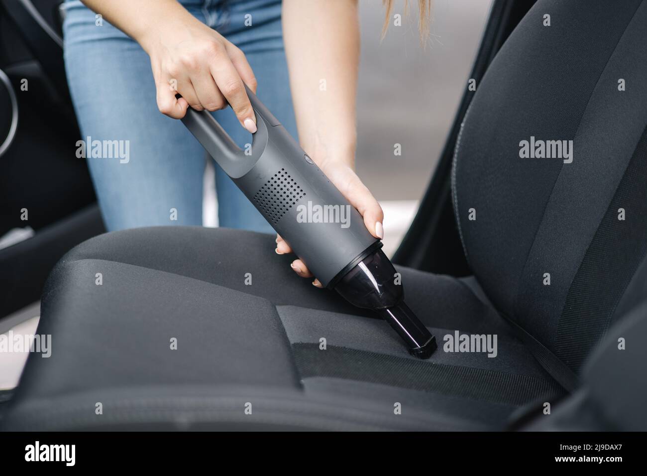 Close up of female using portable vacuum cleaner in her car. Electrical ...