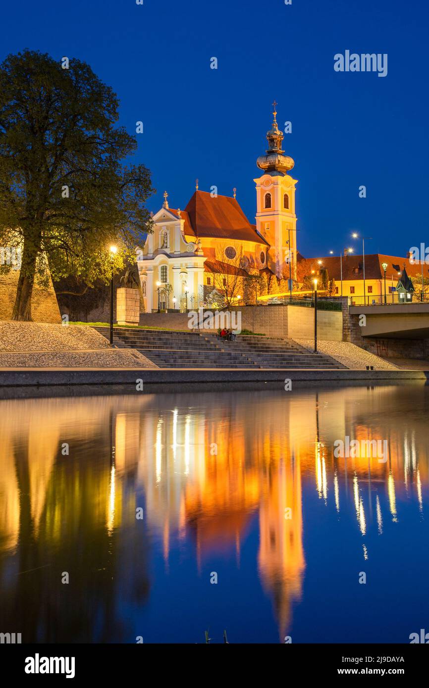 Gyor, city in Hungary, baroque Carmelite church by night reflecting in ...