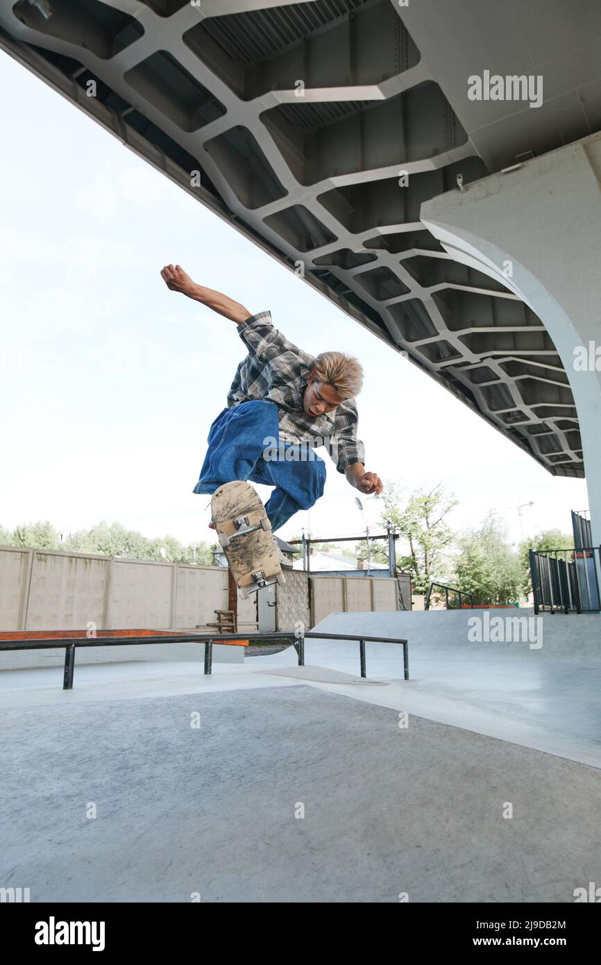 Vertical portrait of teenage boy doing skateboard tricks in air at ...