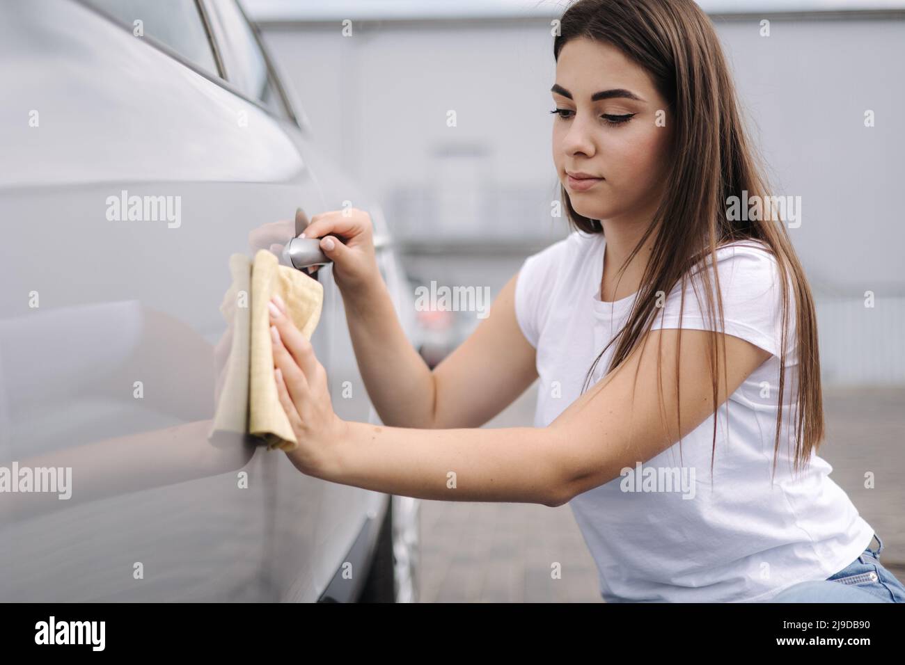 Front view of attractive happy joyful female driver washing her car ...
