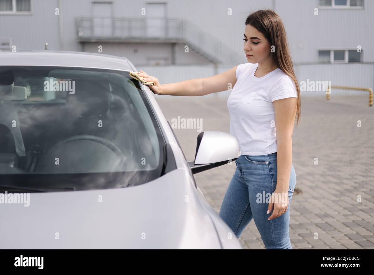 Front view of attractive happy joyful female driver washing her car's ...