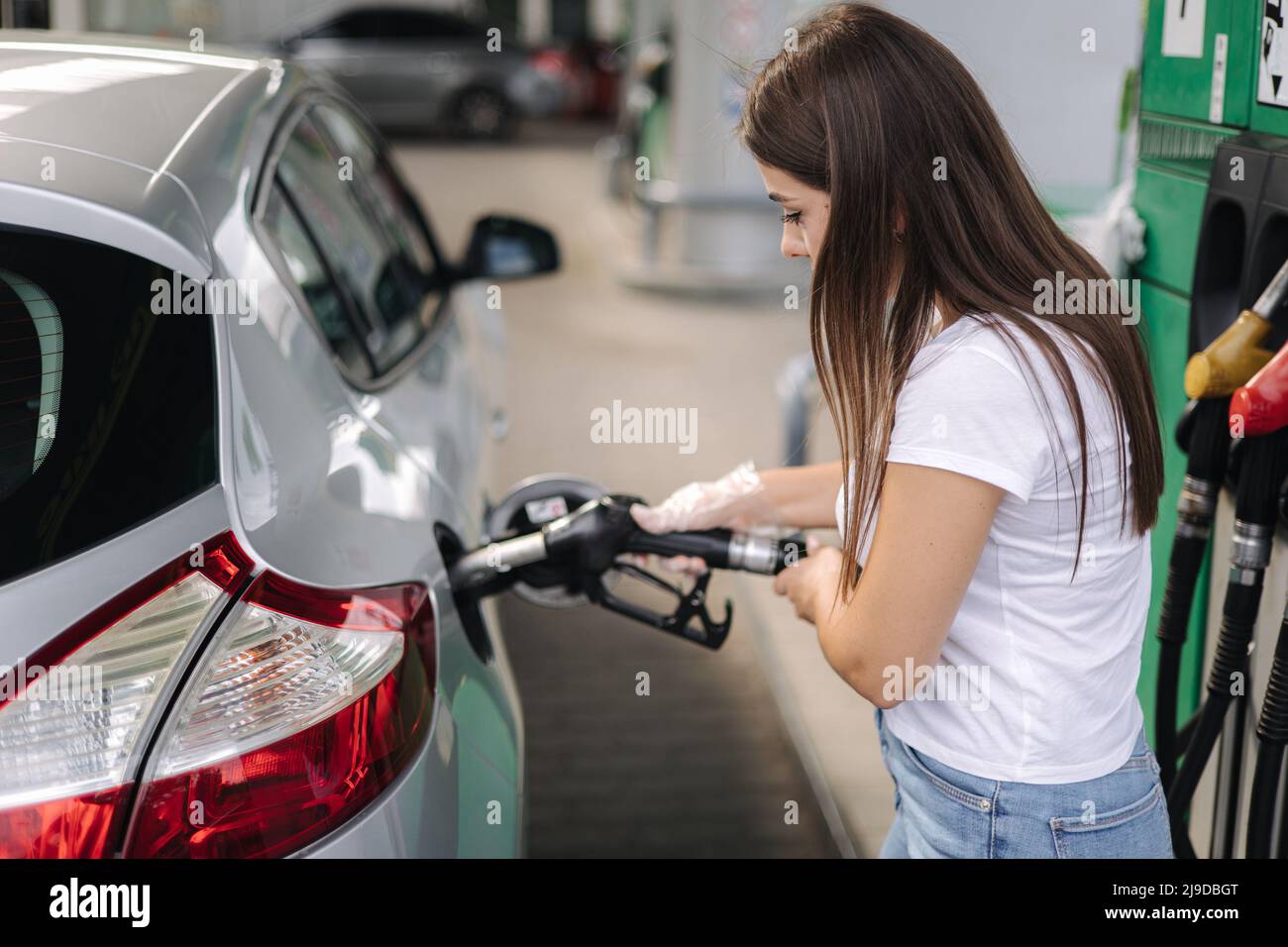 Attractive young woman refueling car at gas station. Female filling ...