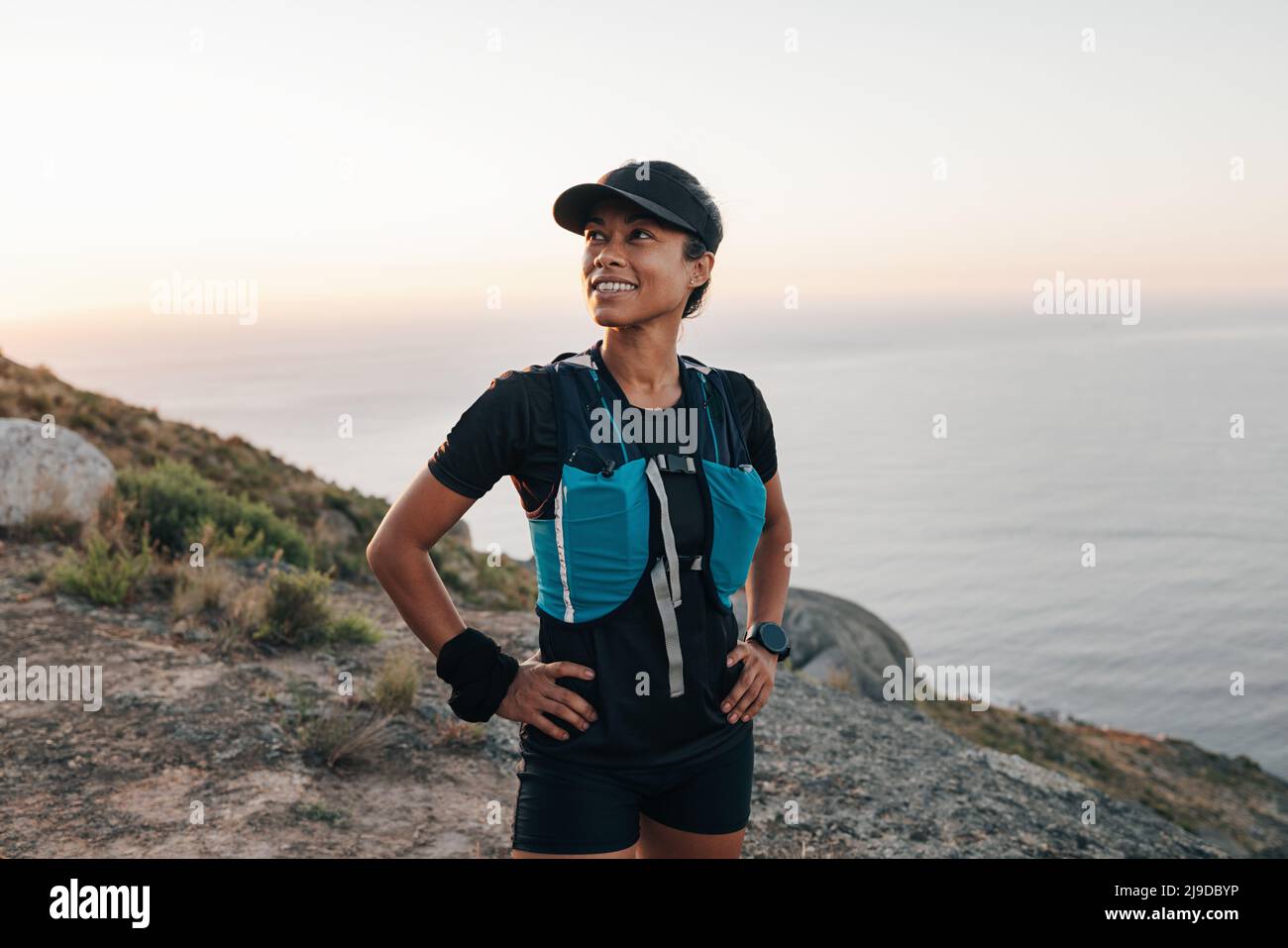 Portrait of a young woman in hiking attire standing in wild terrain and ...