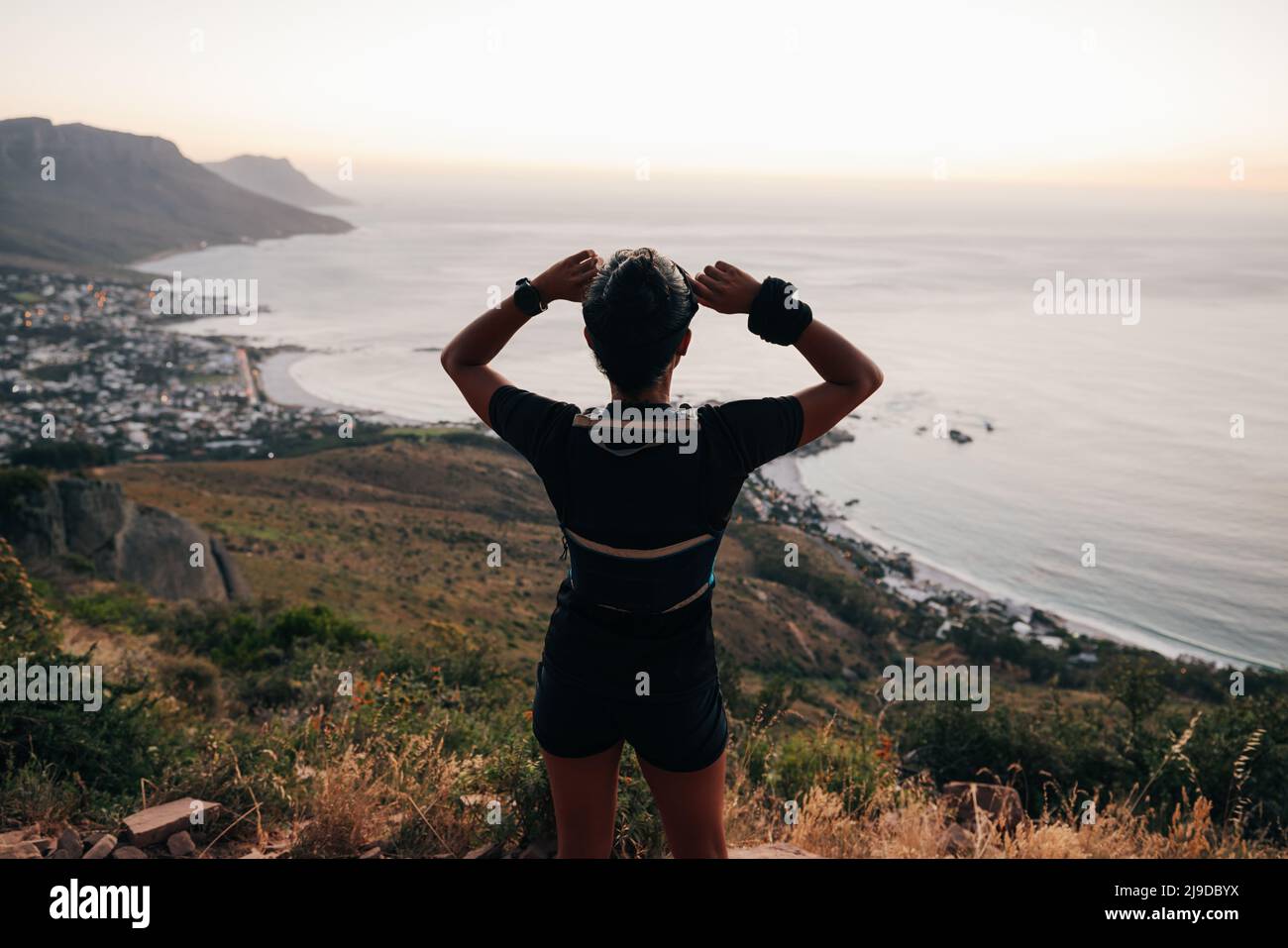 Back view of woman hiker in sportswear enjoying view and sunset after ...