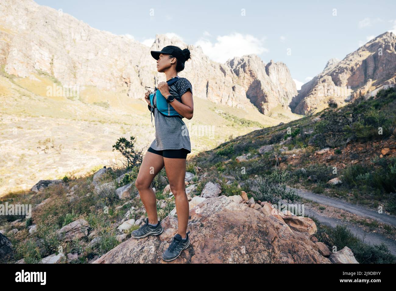 Side view of trail runner in sports wear standing in valley. Young ...