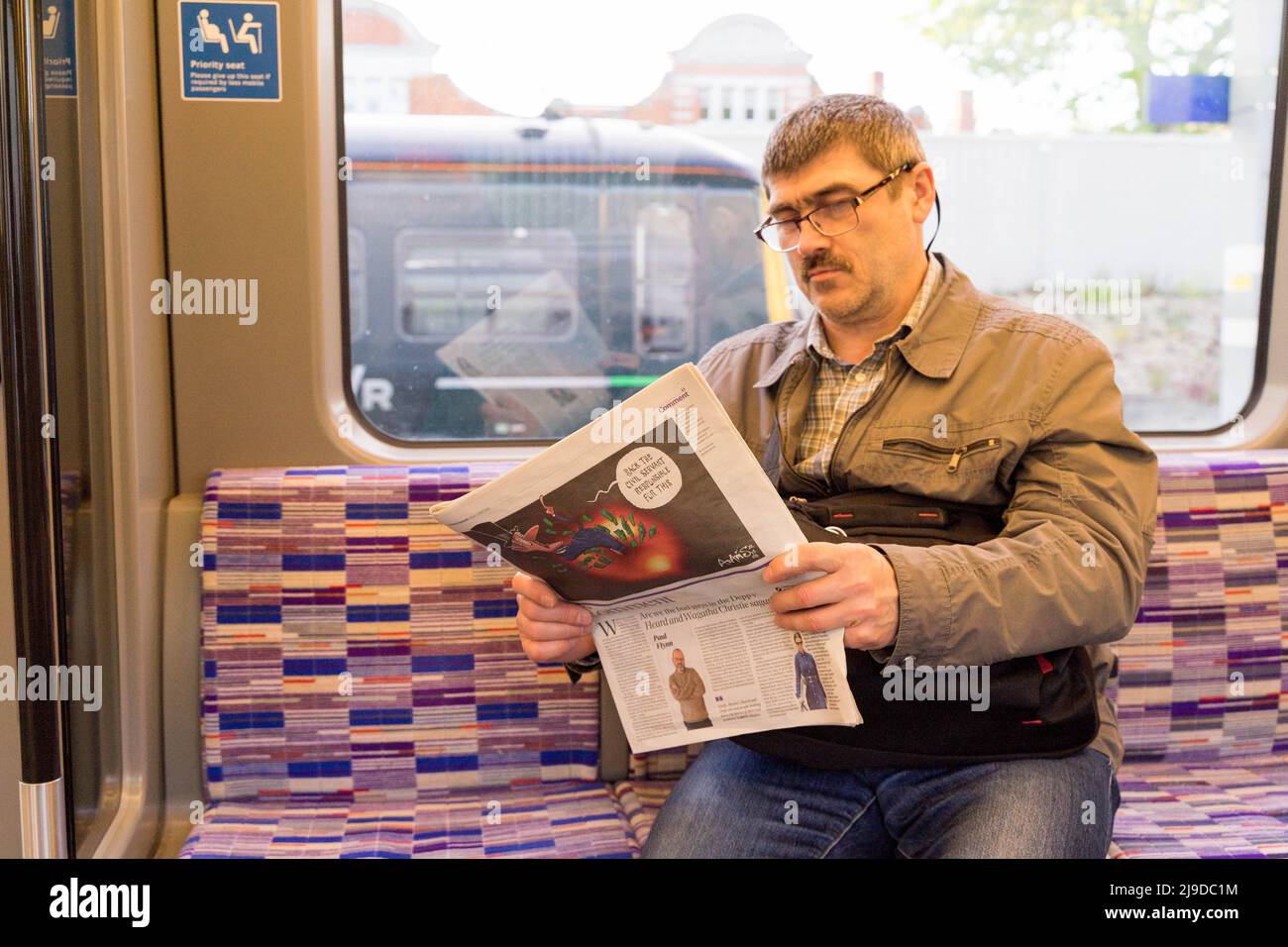 train passenger reading a newspaper on Elizabeth line , Crossrail ...