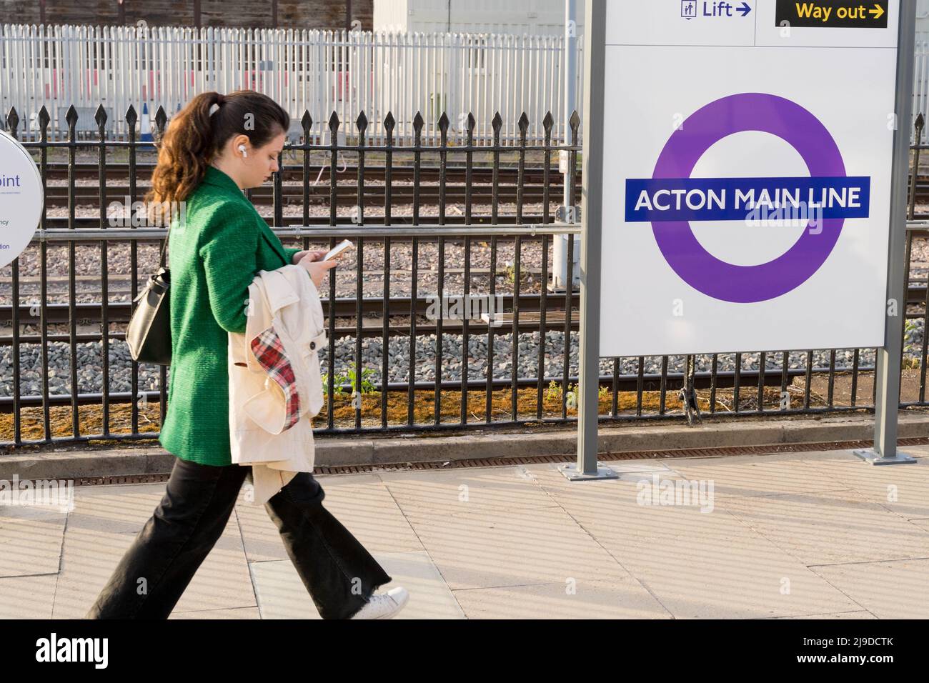 Woman in green jacket walk on platform at Acton Main Line station for ...