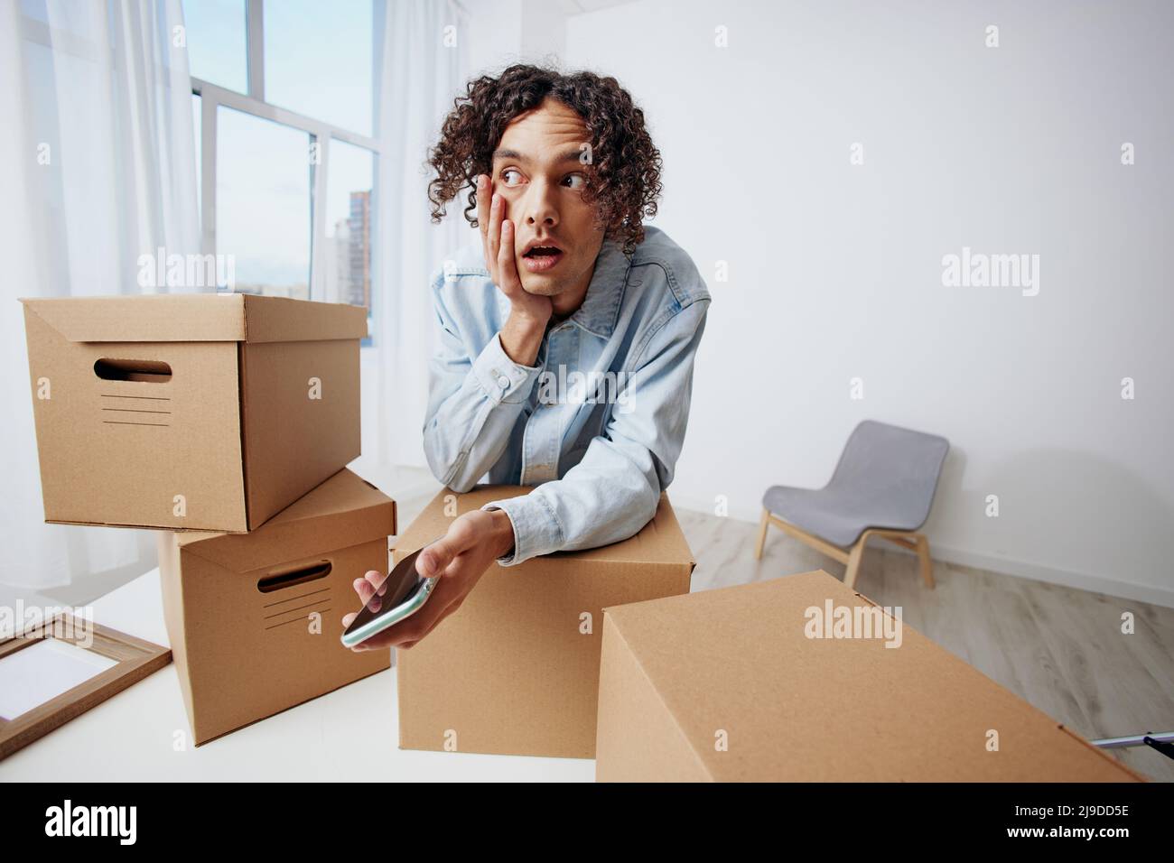 handsome guy cardboard boxes in the room unpacking with phone sorting ...