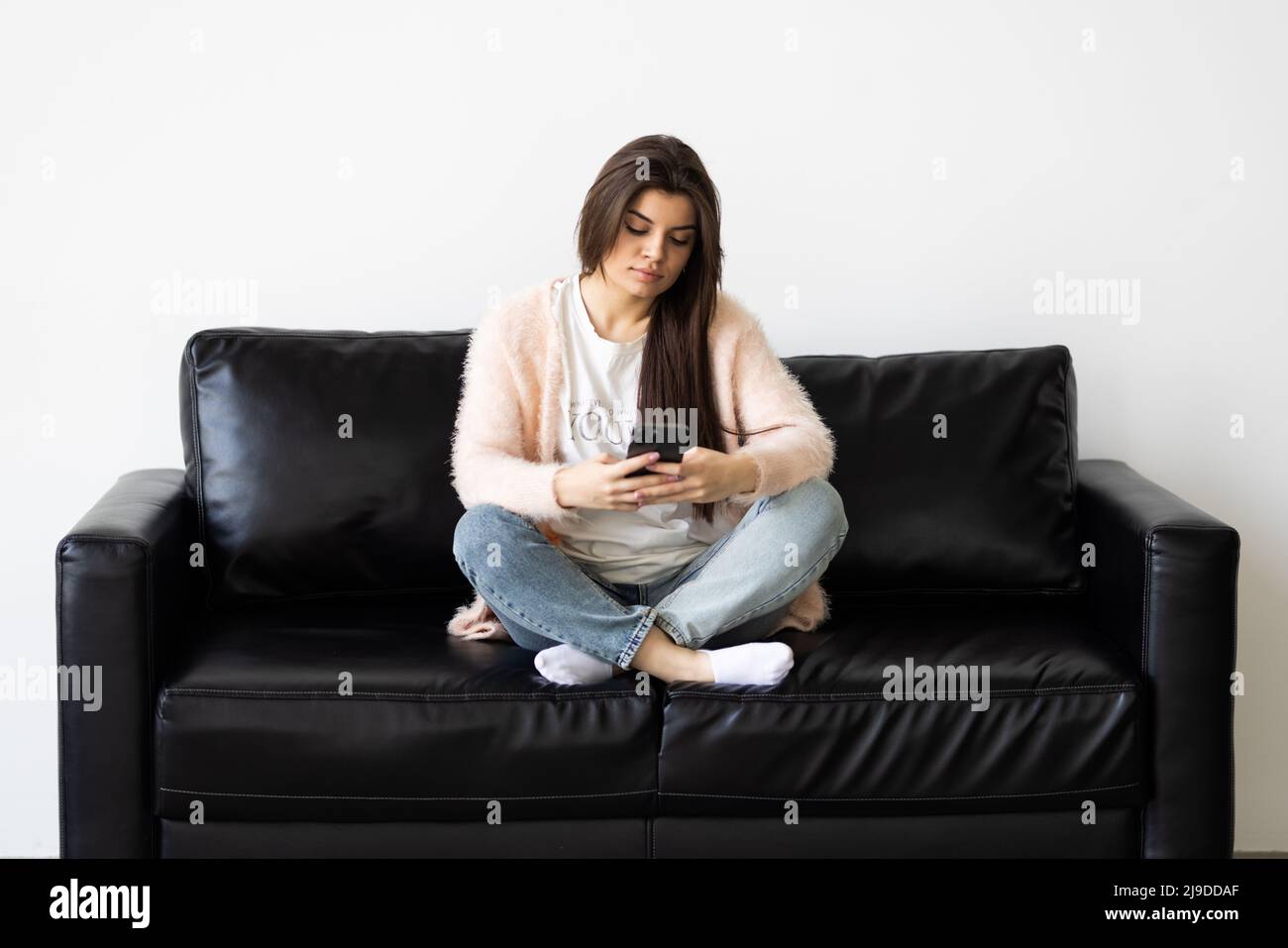Portrait young woman use smart mobile phone on sofa in living room ...