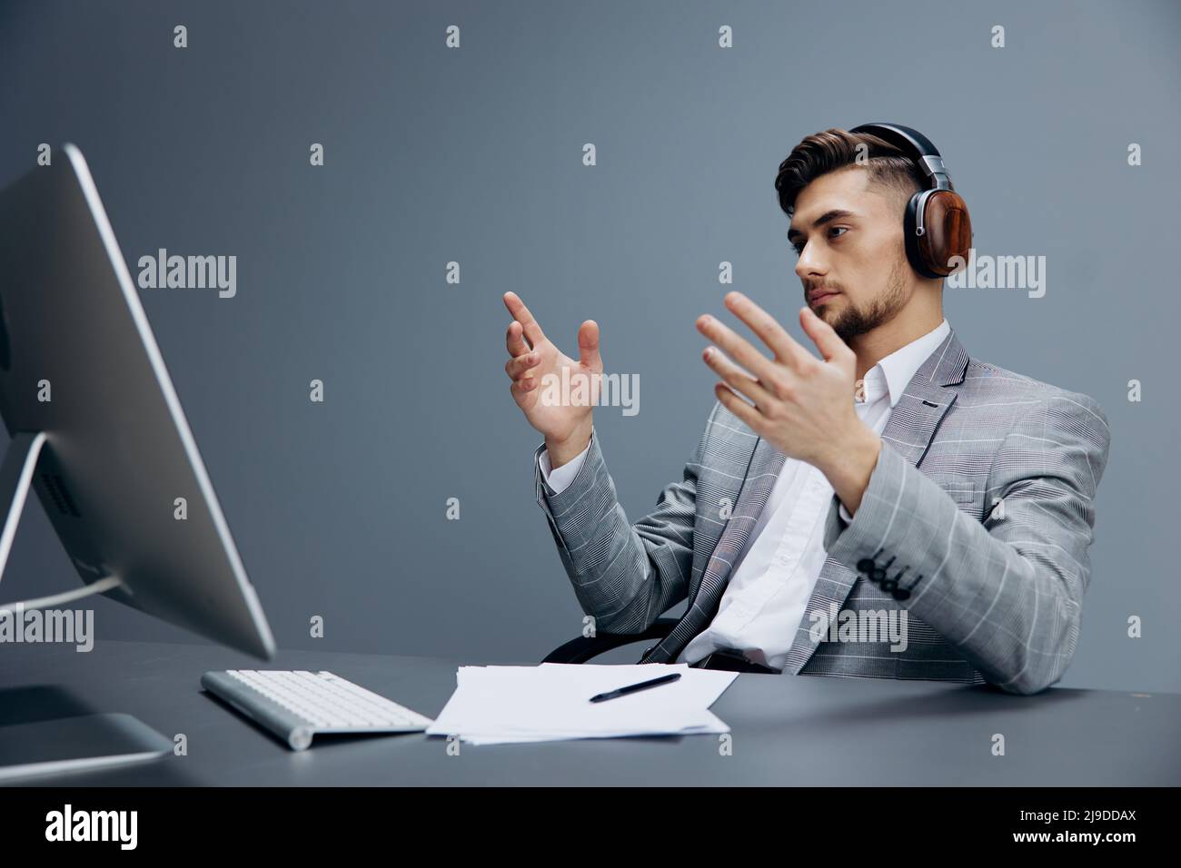 businessmen in headphones in a gray suit sits in front of a computer ...